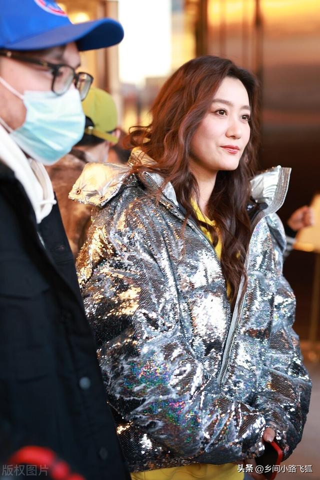 Tan Jing went out at the hotel, wearing a silver padded jacket in a ...